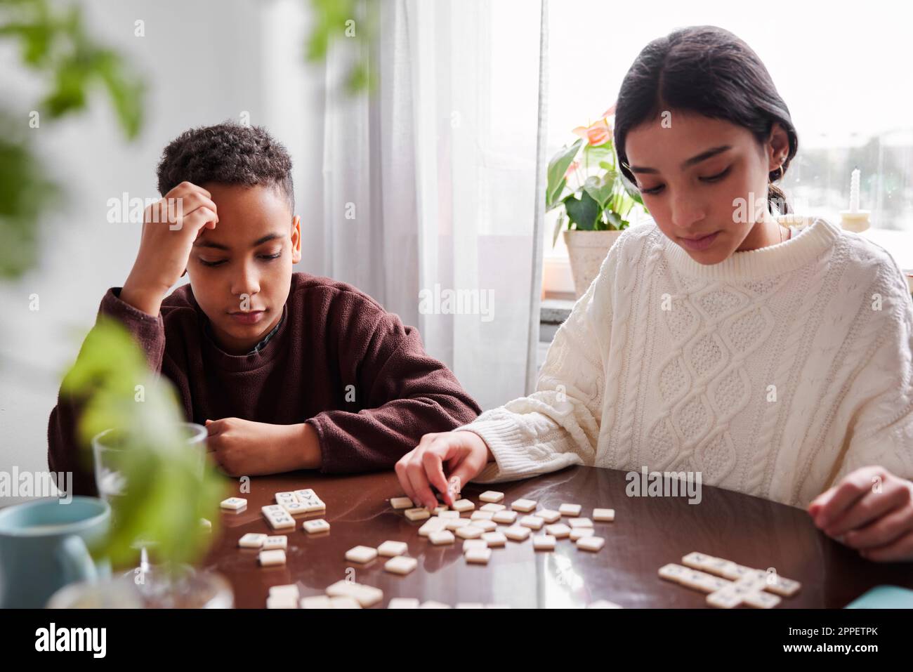 Girl and boy playing scrabble at dining table Stock Photo - Alamy