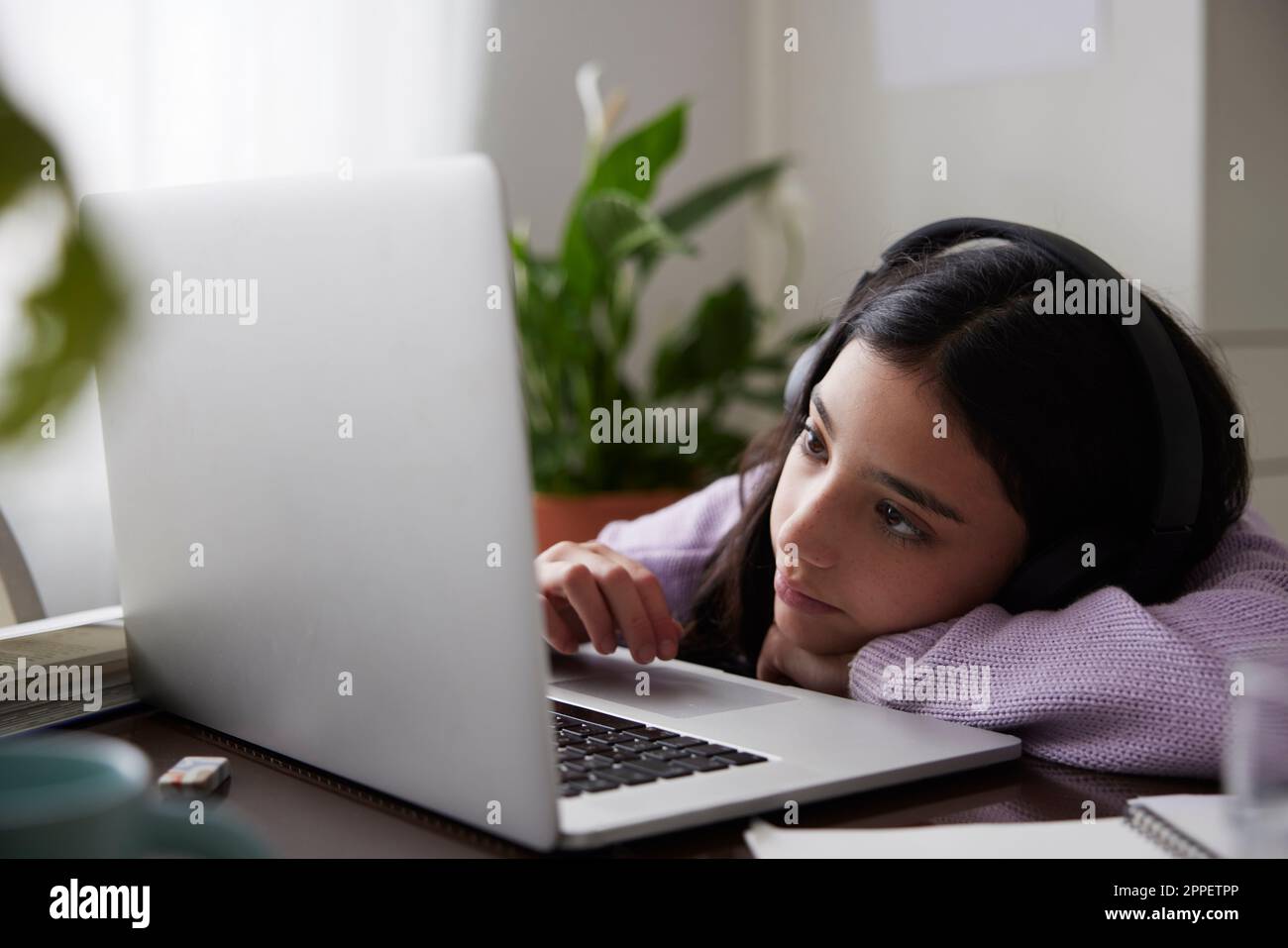 Girl doing homework with laptop at dining table Stock Photo - Alamy