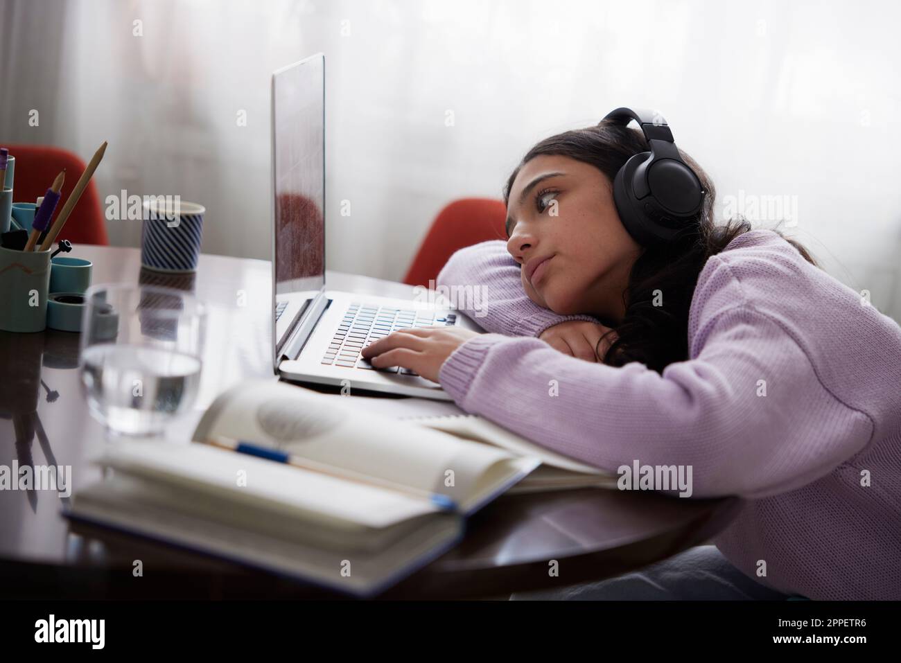 Girl doing homework with laptop at dining table Stock Photo - Alamy