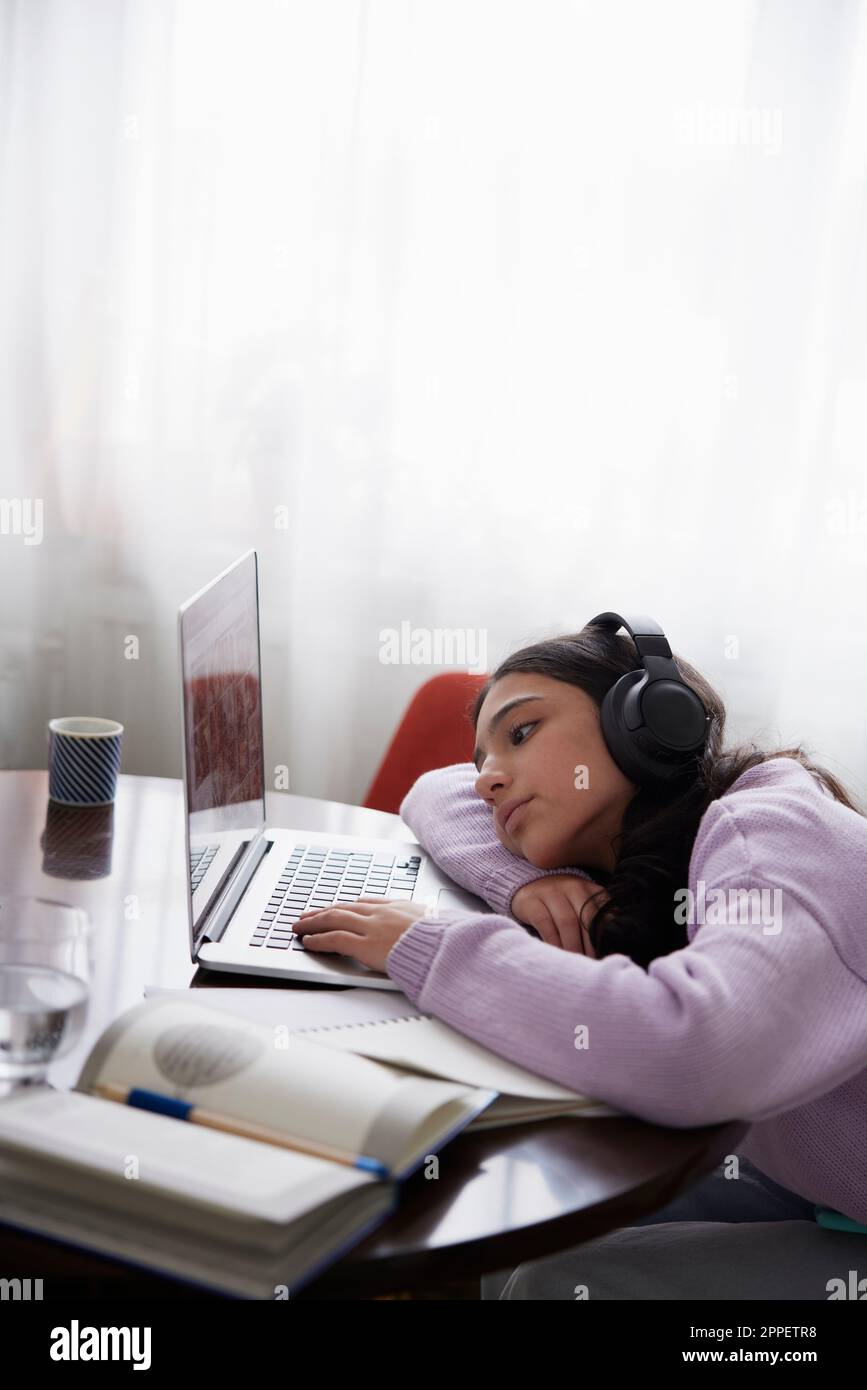 Girl doing homework with laptop at dining table Stock Photo - Alamy
