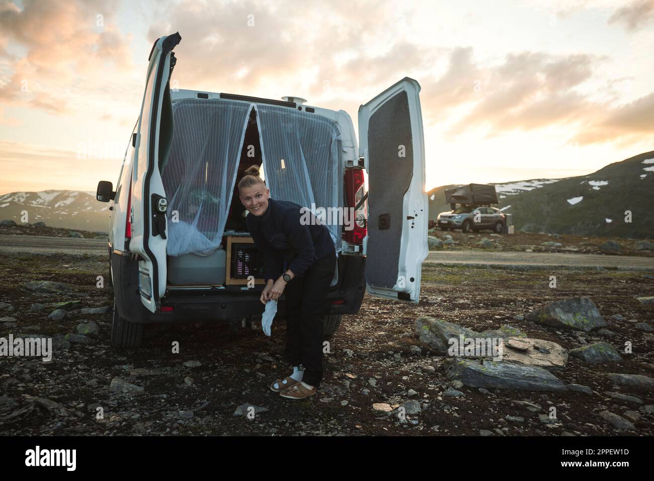 Smiling woman standing in front of camper van Stock Photo - Alamy