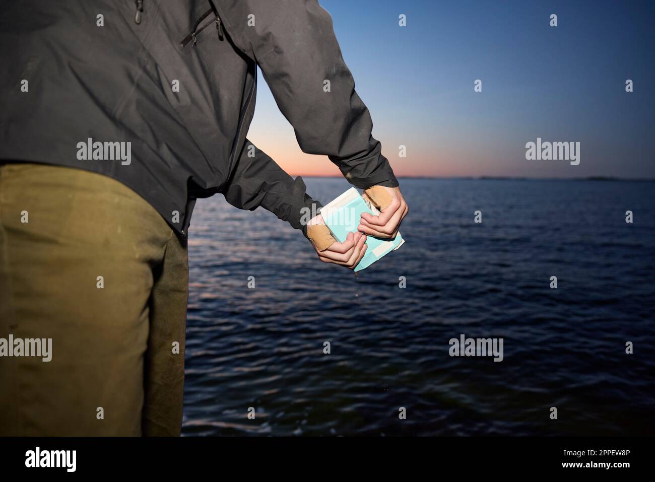 Mid section of person holding container at sea Stock Photo - Alamy