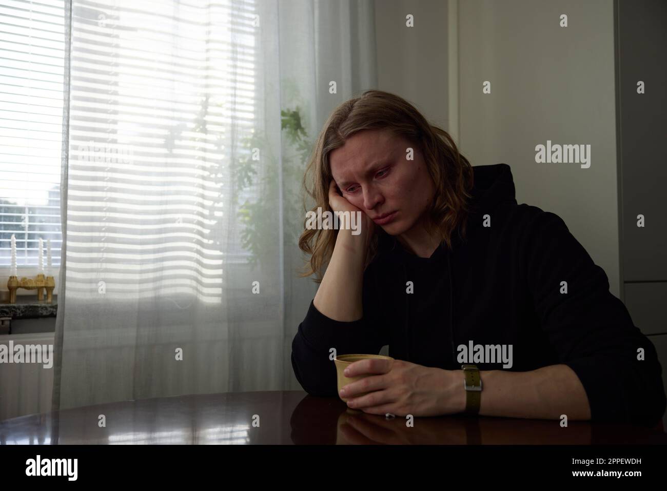 Sad woman sitting at table Stock Photo - Alamy