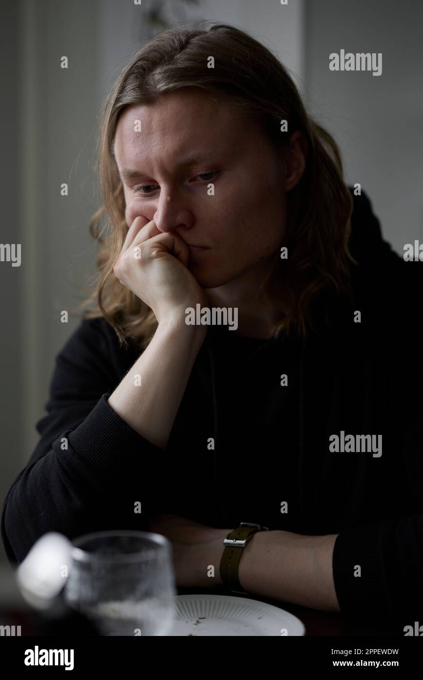 Sad woman sitting at table Stock Photo - Alamy
