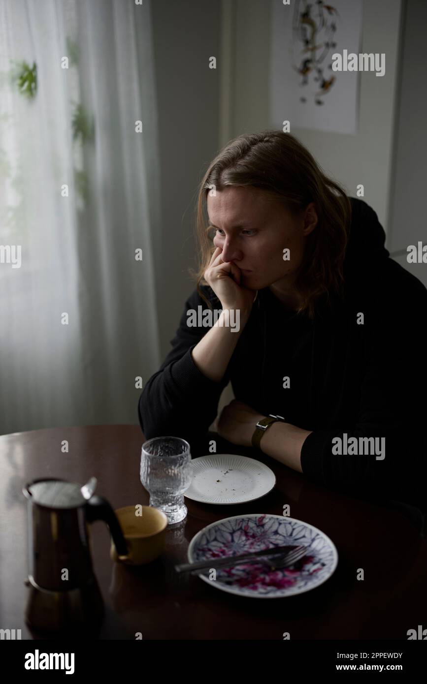 Sad woman sitting at table Stock Photo - Alamy