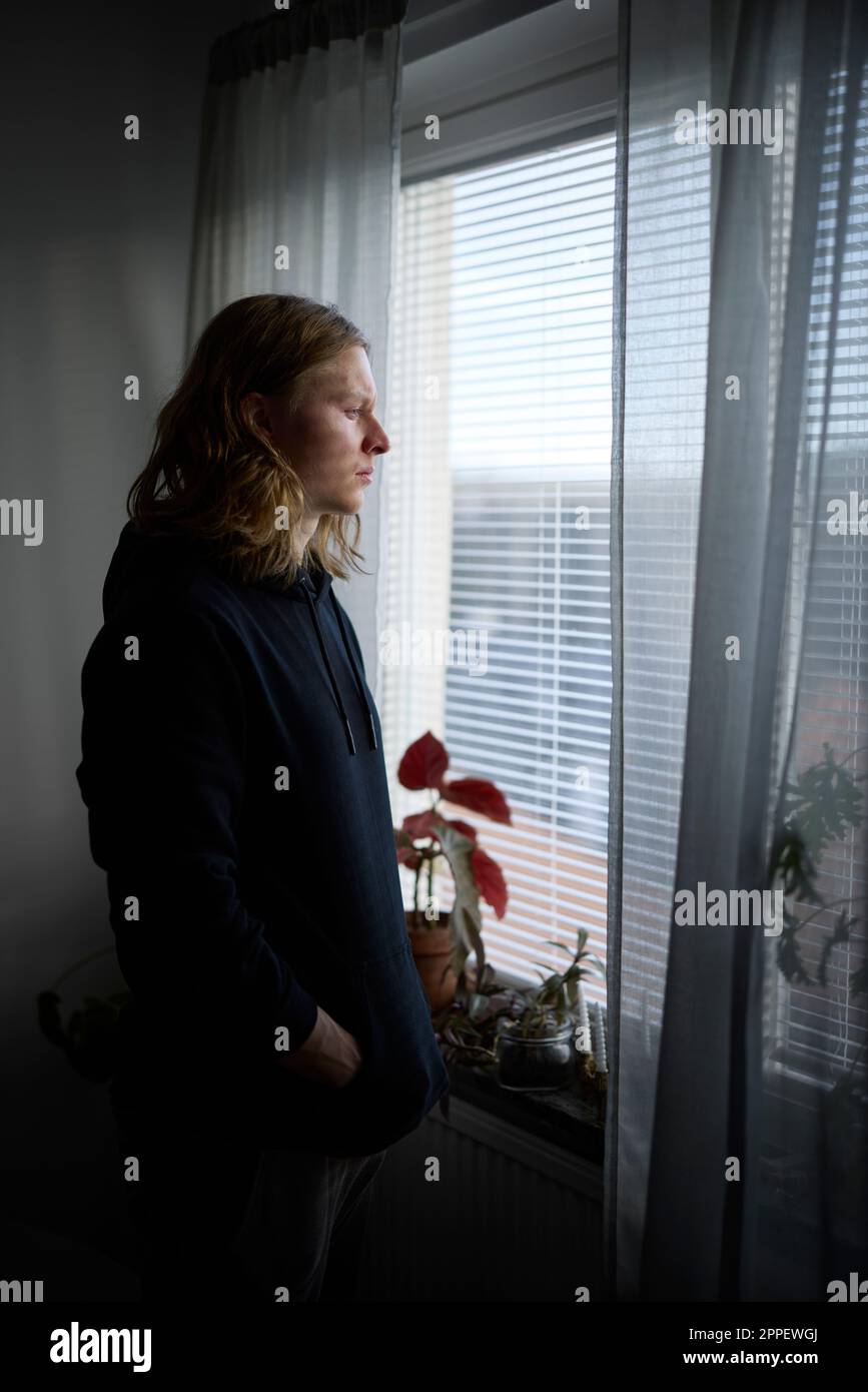 Sad woman looking through window Stock Photo - Alamy