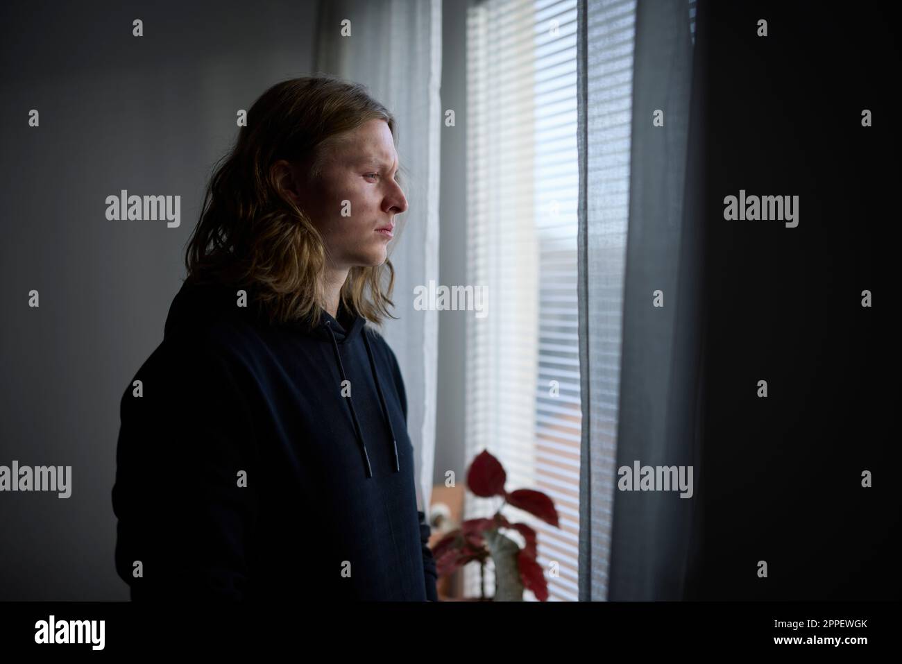 Sad woman looking through window Stock Photo - Alamy