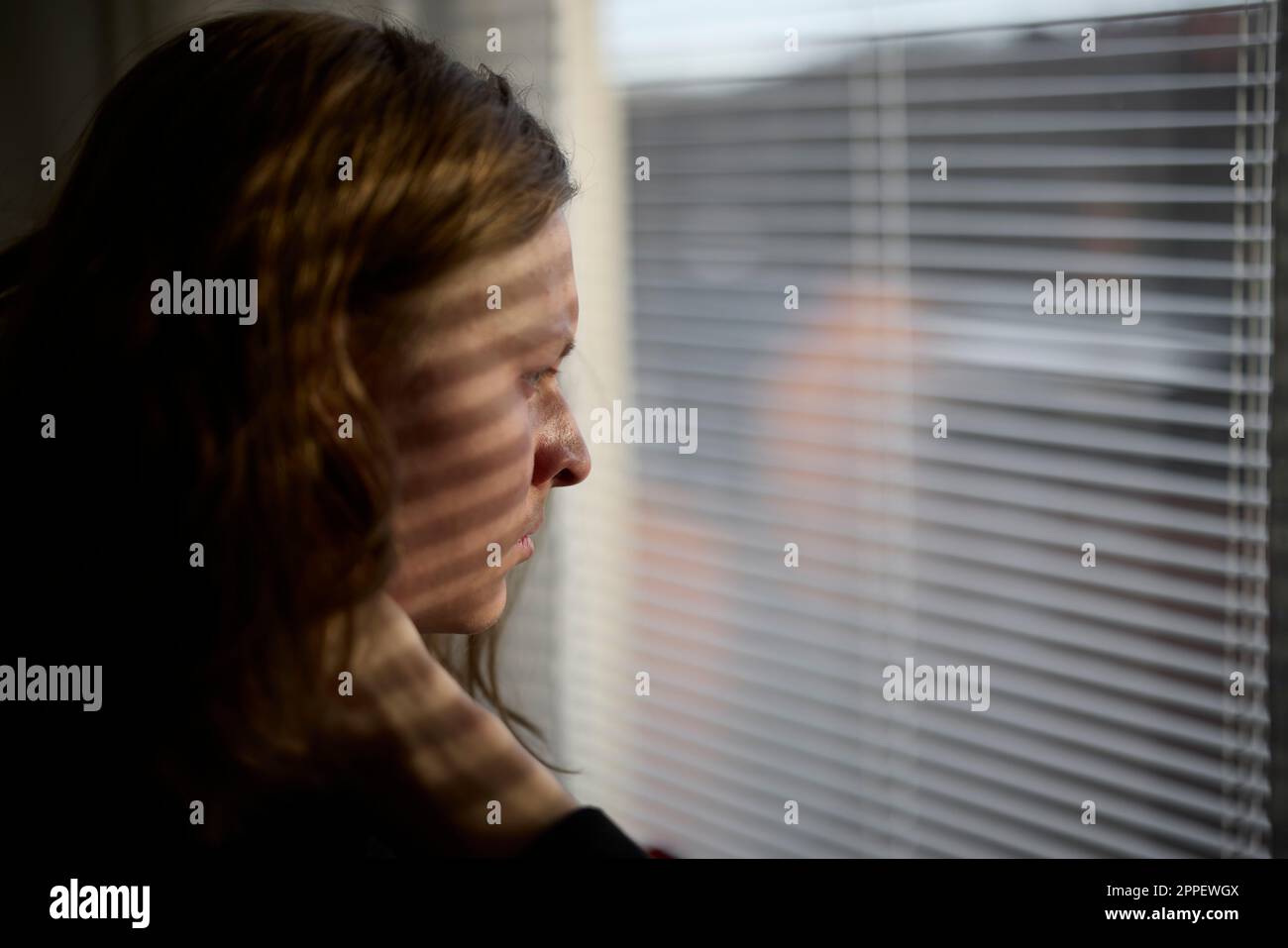 View of woman looking through window Stock Photo - Alamy