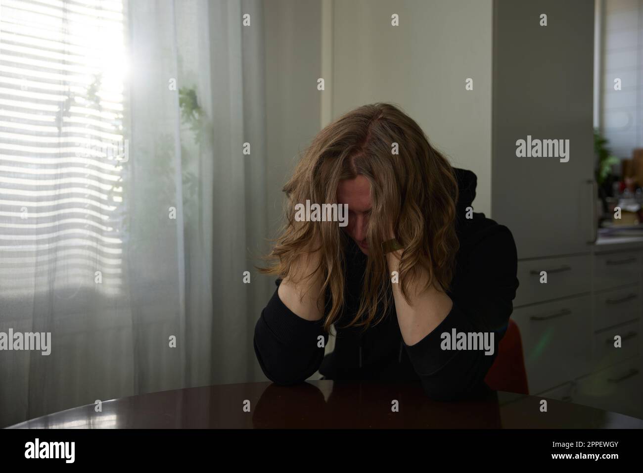 Sad woman sitting at table Stock Photo - Alamy