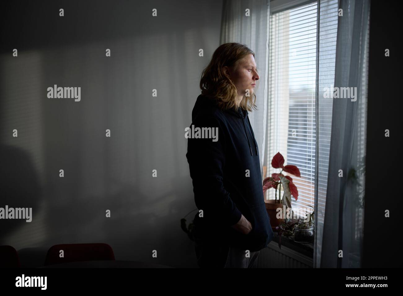 Sad woman looking through window Stock Photo - Alamy