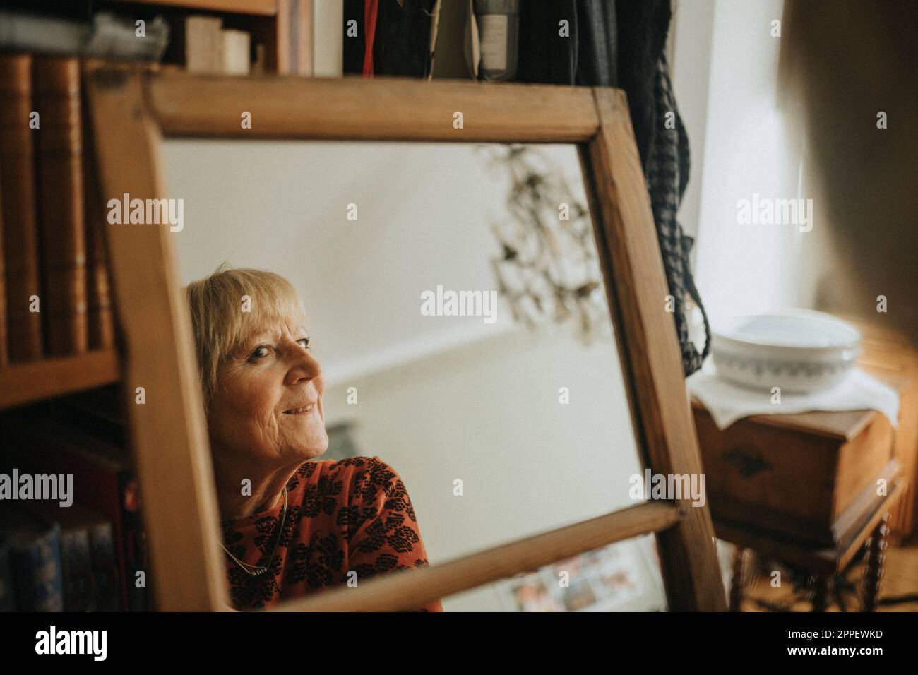 Senior woman looking in mirror Stock Photo - Alamy