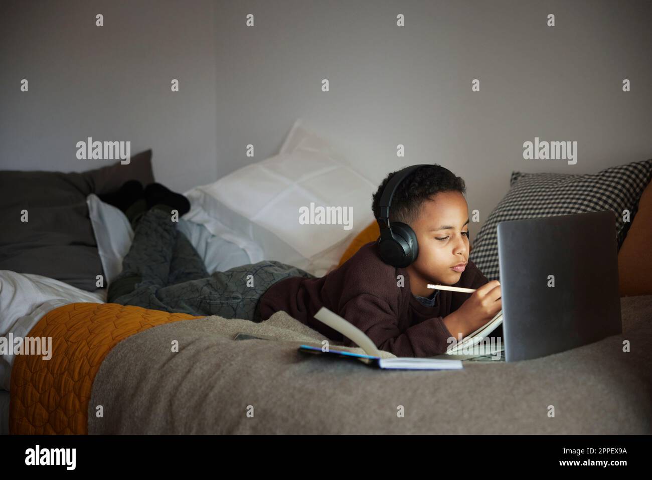 Boy doing homework with laptop in his bedroom Stock Photo - Alamy