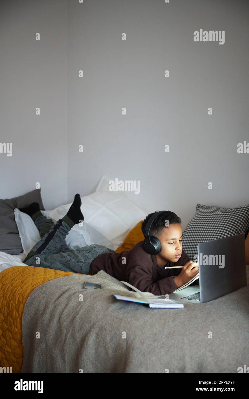 Boy doing homework with laptop in his bedroom Stock Photo - Alamy