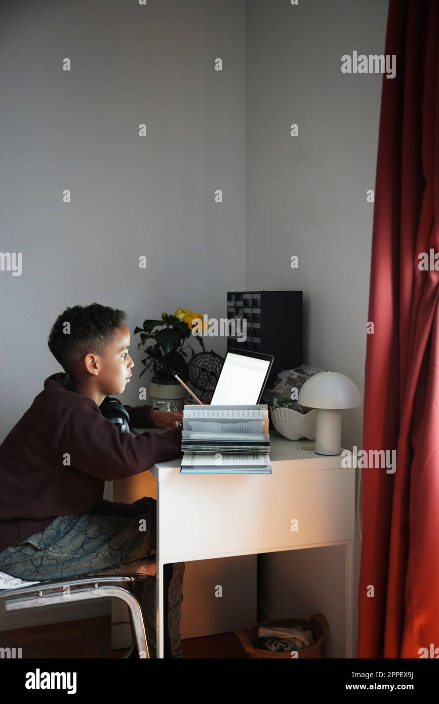 Boy doing homework with laptop Stock Photo - Alamy