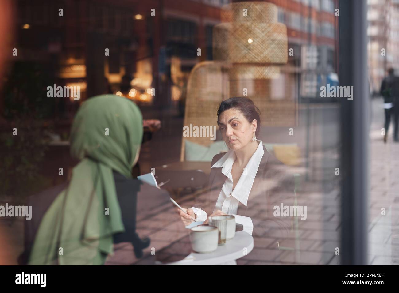 View through window of women in cafe Stock Photo - Alamy