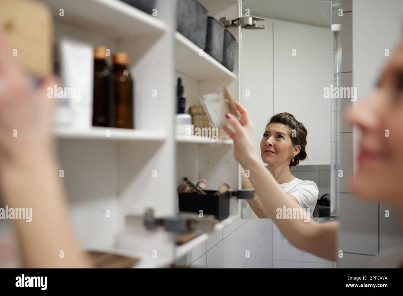 Woman putting standing in front of open cupboard Stock Photo - Alamy