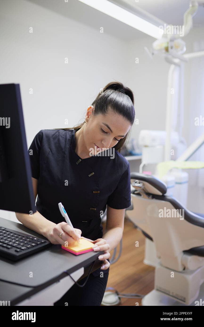 Female dentist writing in office Stock Photo - Alamy