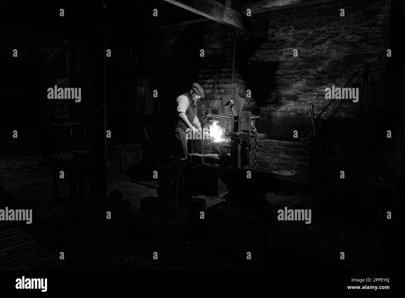 Chain maker hammering out a chain link causing sparks to fly, Red at ...