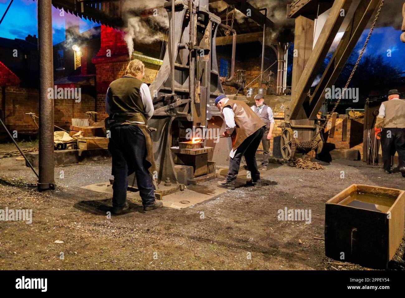 A volunteer forging hot metal under a Anchor Forge Steam-Powered Hammer ...
