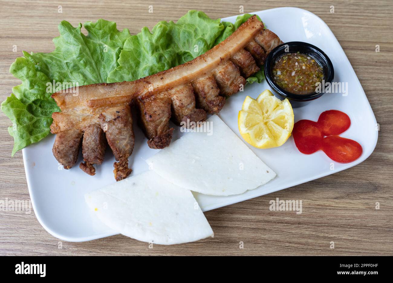 Typical Colombian dish. Chicharron with spicy sauce decorated with ...