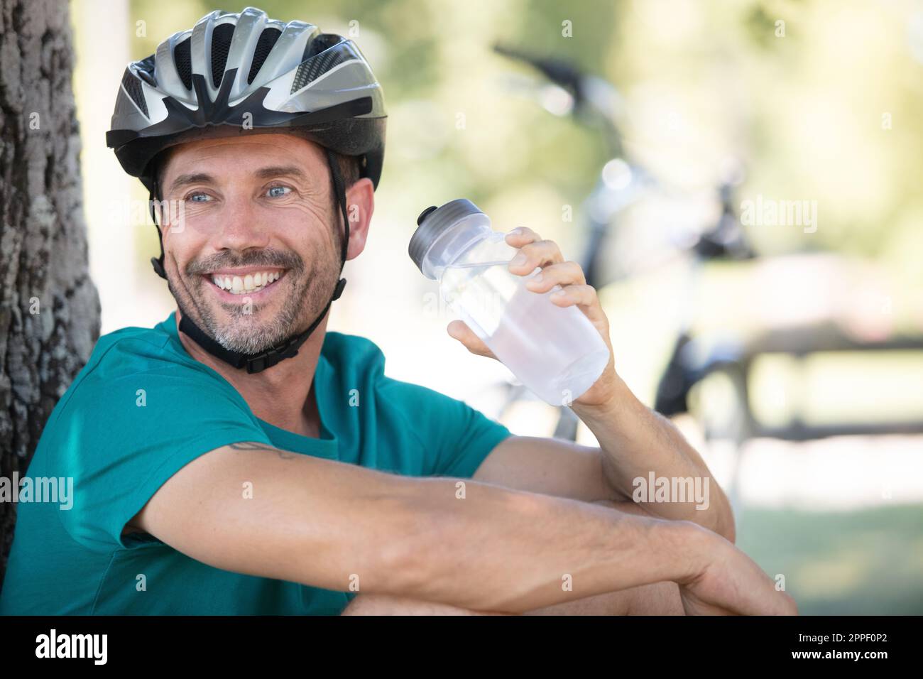 handsome man riding bike and drinking water resting Stock Photo - Alamy