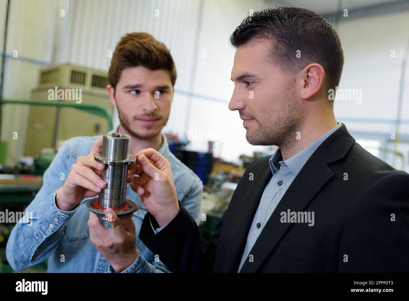 two workers examining metal shaft Stock Photo - Alamy