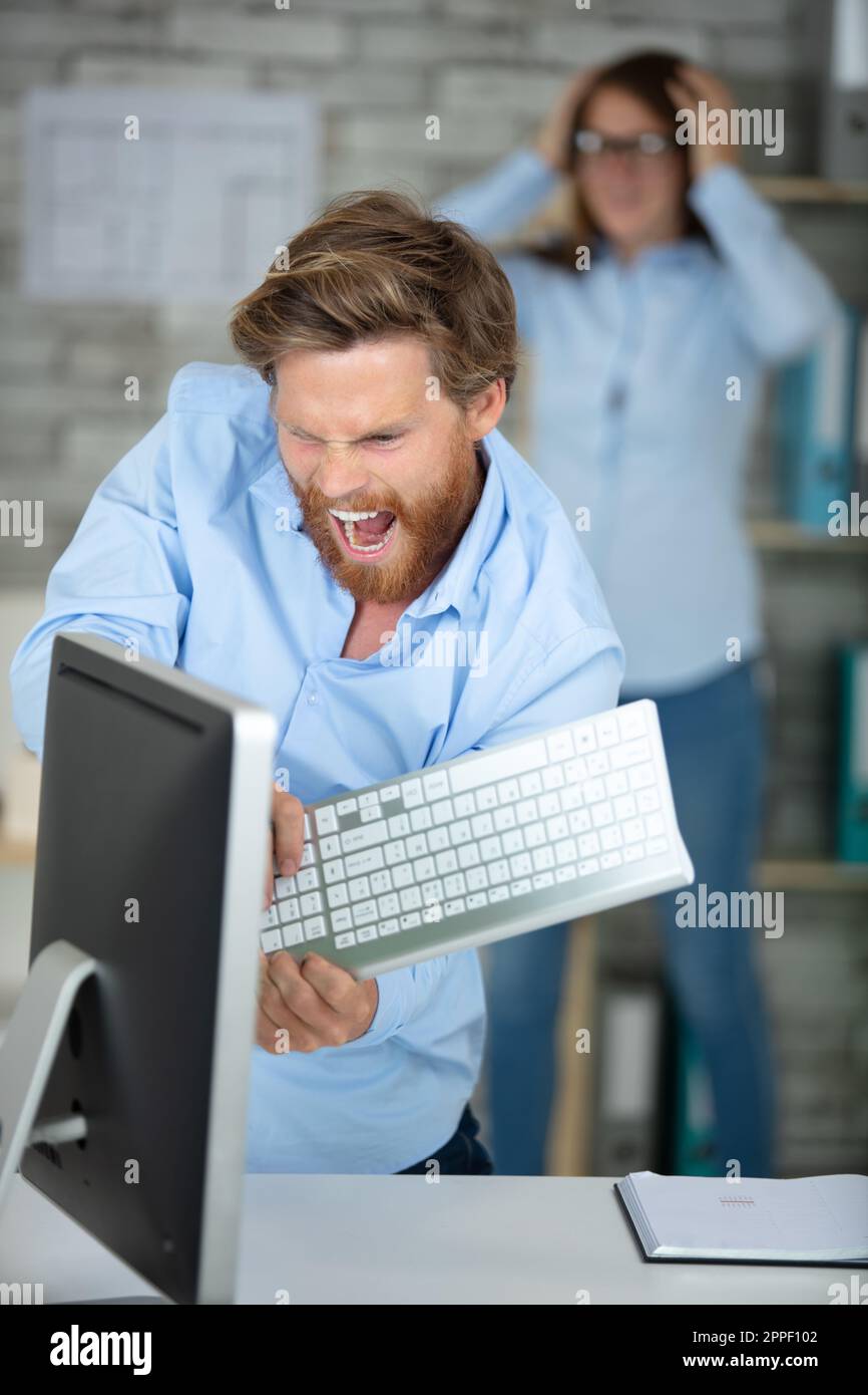 angry businessman smashes computer with keyboard Stock Photo - Alamy