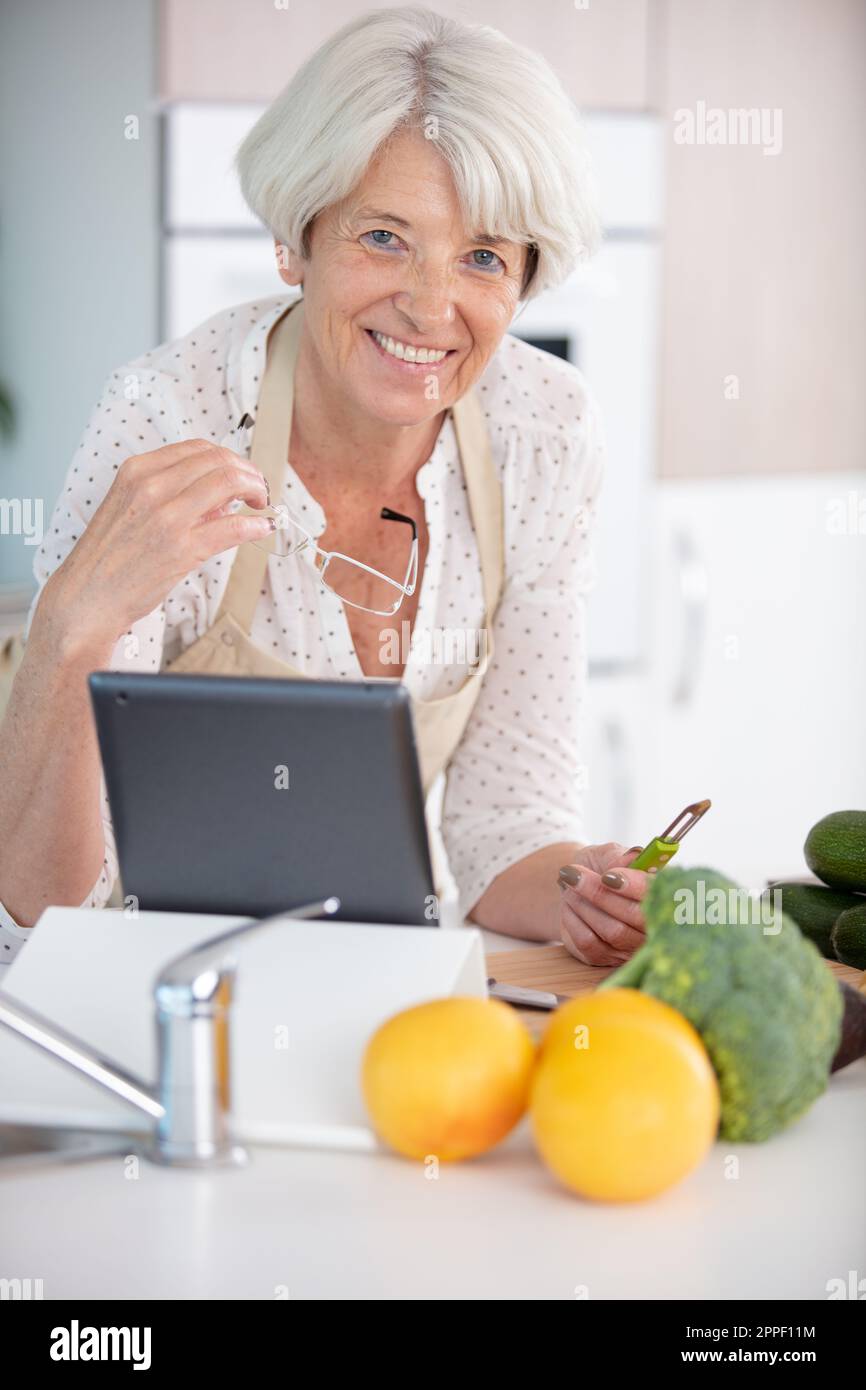 senior woman cooking with help of recipe on tablet Stock Photo - Alamy
