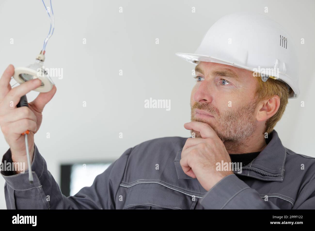 confused contractor installing a spotlight Stock Photo - Alamy