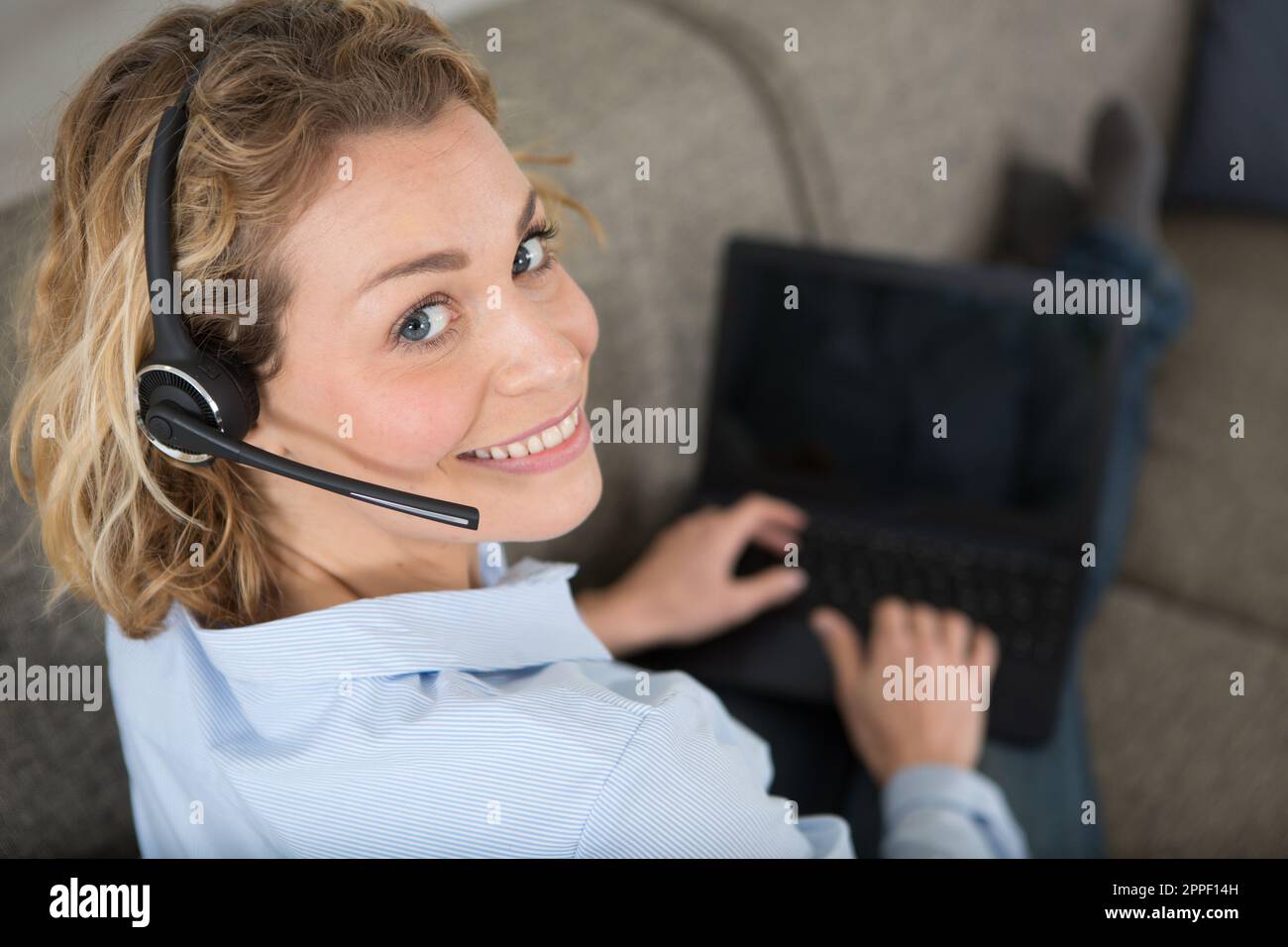 freelance worker on sofa using laptop and wearing headset Stock Photo ...