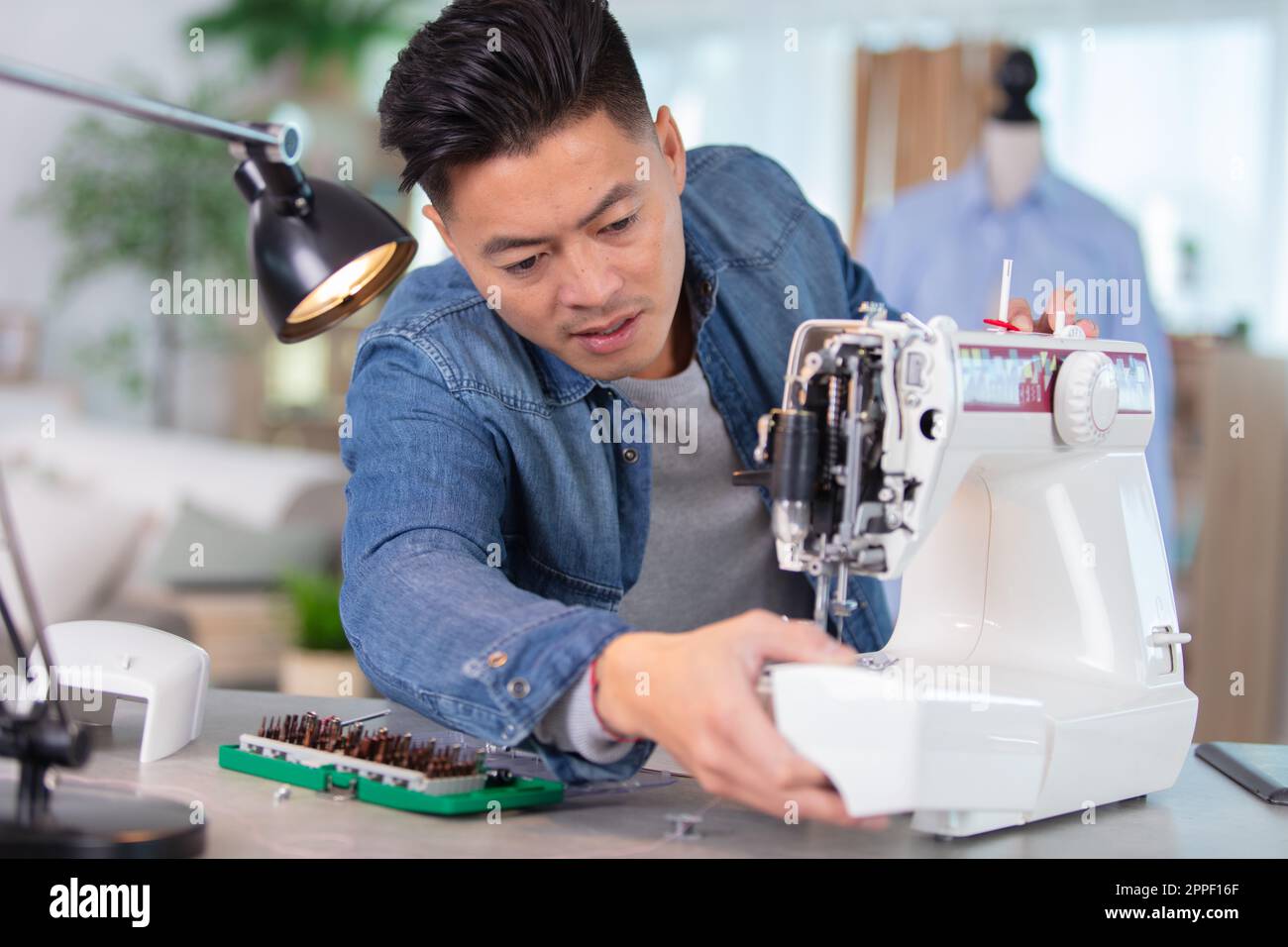 male dressmaker repairing sewing machine Stock Photo - Alamy