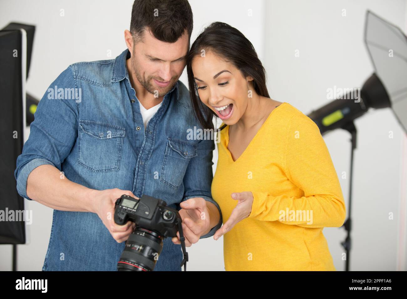 photographer reviewing photos and showing them to positive female model ...