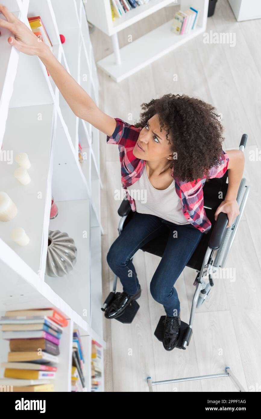 disabled lady struggling to reach book from high shelf Stock Photo - Alamy