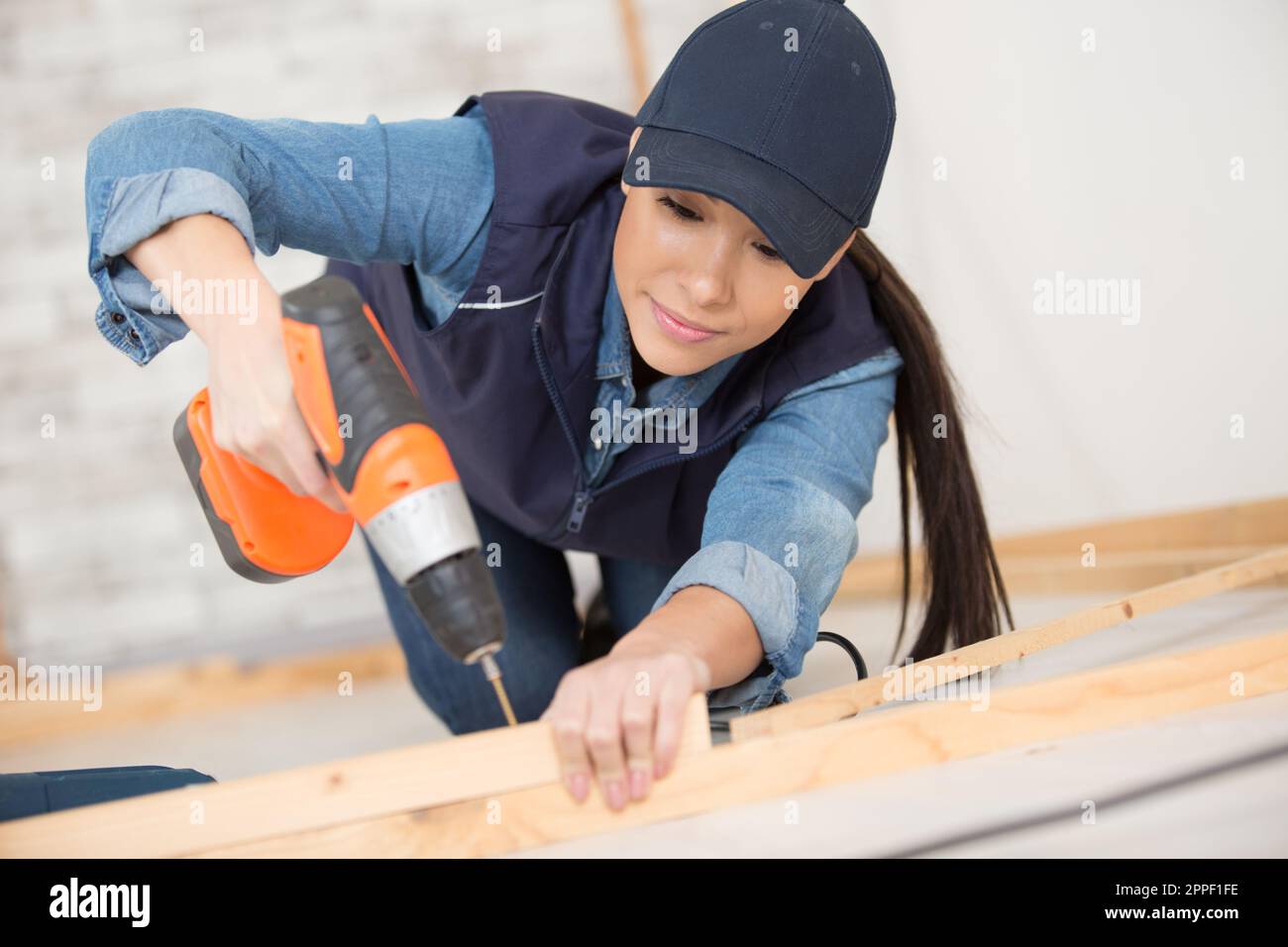 female carpenter using a drill on a wood house structure Stock Photo ...