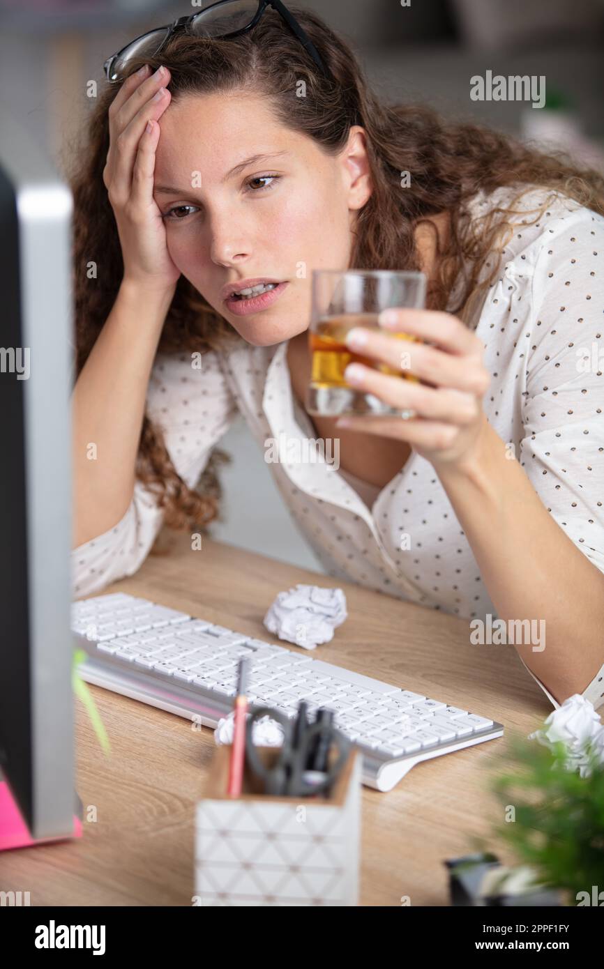 drunk young woman drinking whiskey and working on her computer Stock ...