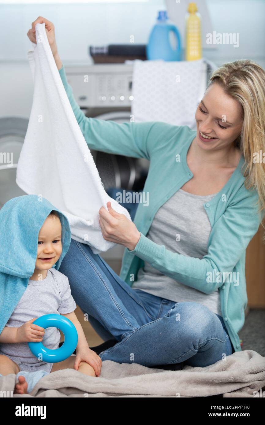 mother and baby loading clothes into washing machine Stock Photo - Alamy