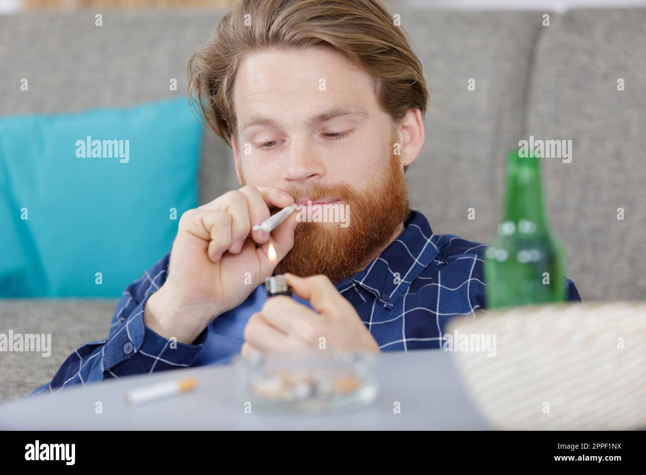 stoned man lighting a joint in his home Stock Photo - Alamy