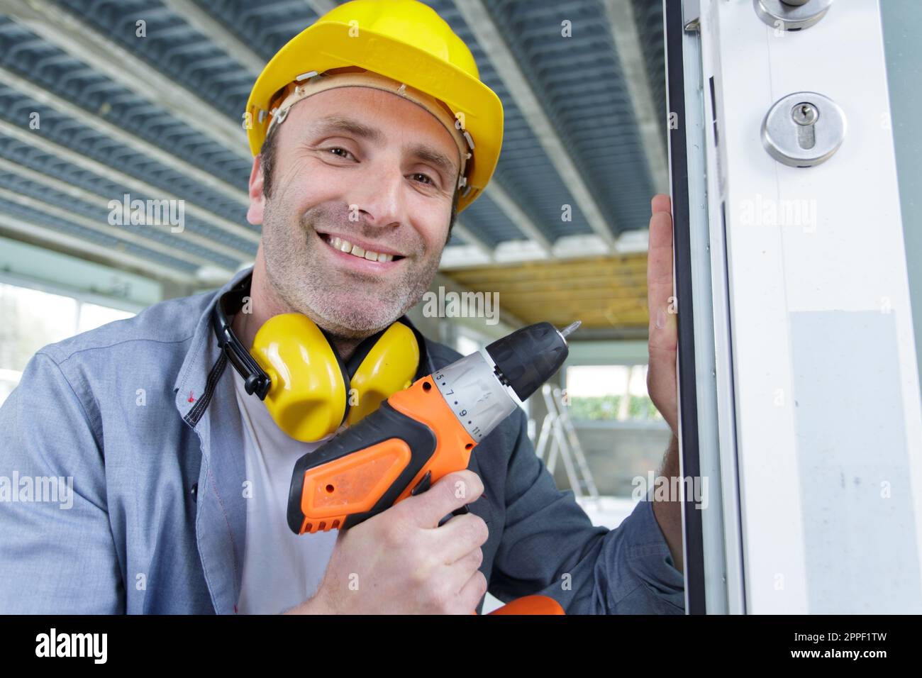 construction worker using drill while installing window indoors Stock ...