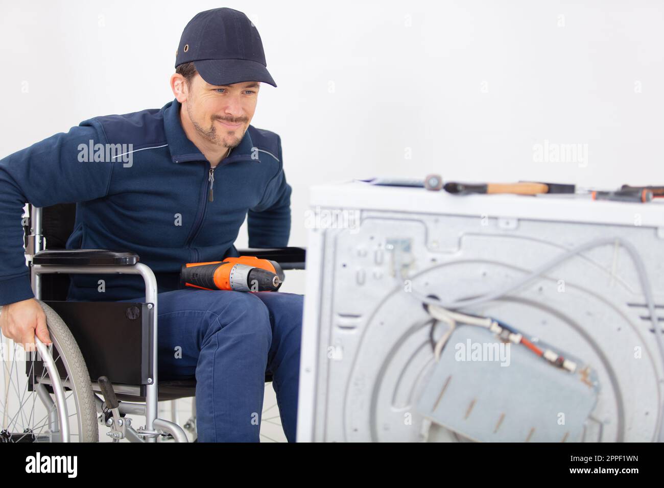 man in wheelchair repairs a washing machine Stock Photo - Alamy