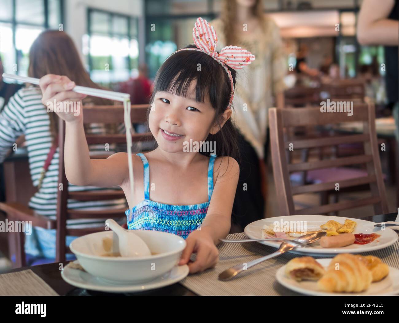 Happy Asian child eating delicious noodle with chopstick, in the ...