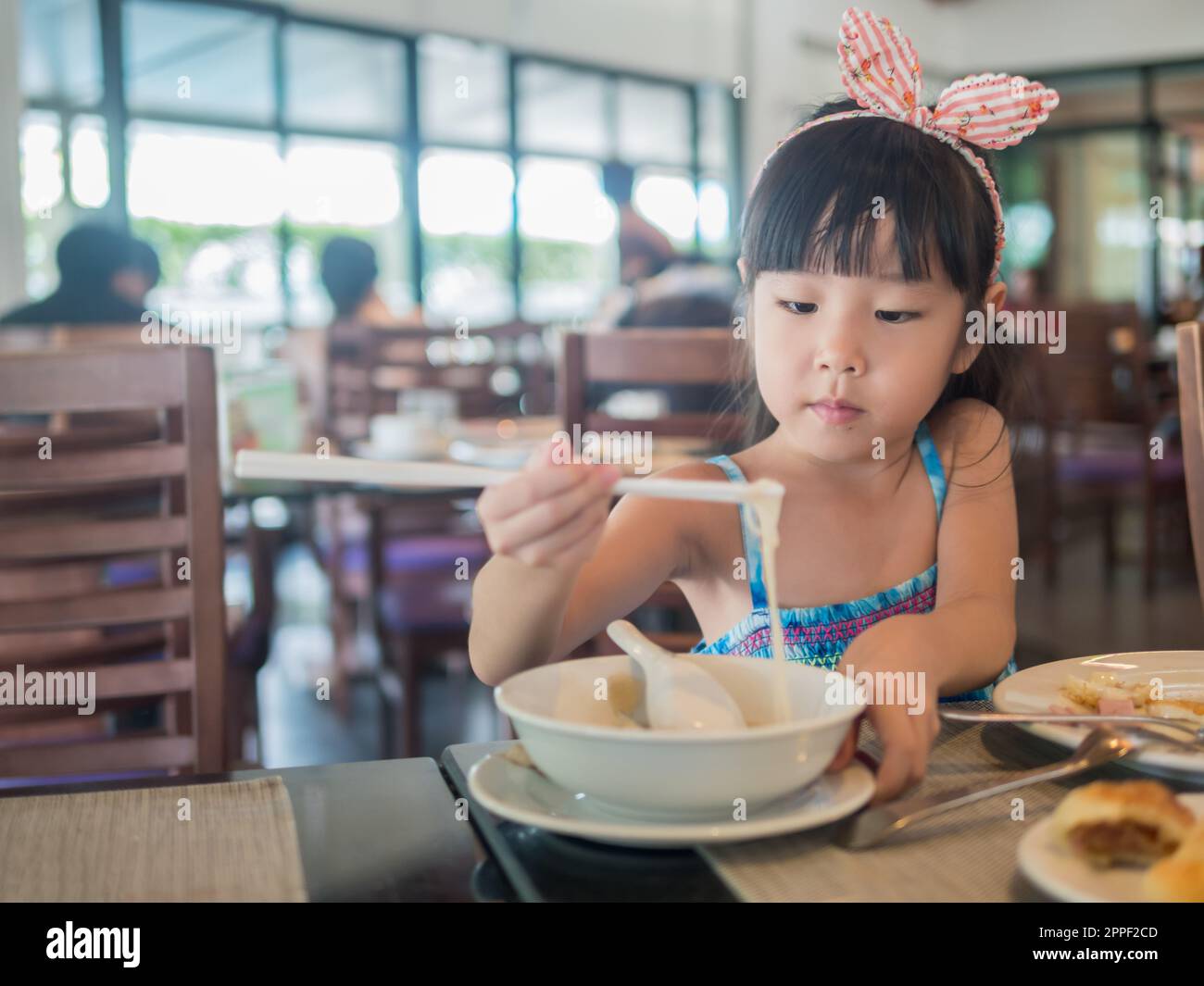 Happy Asian child eating delicious noodle with chopstick, in the ...
