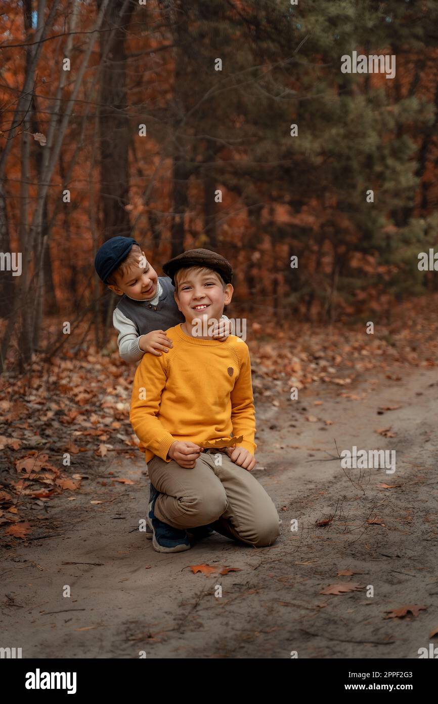 The kid hugs his older brother. Children in retro clothes in the forest ...