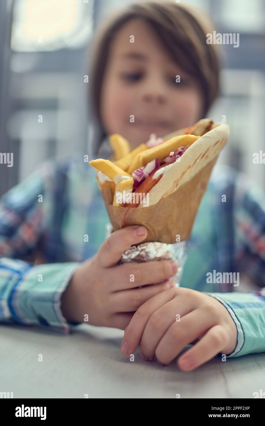 Cute little boy eating Greek gyros sandwich in a fast food restaurant ...