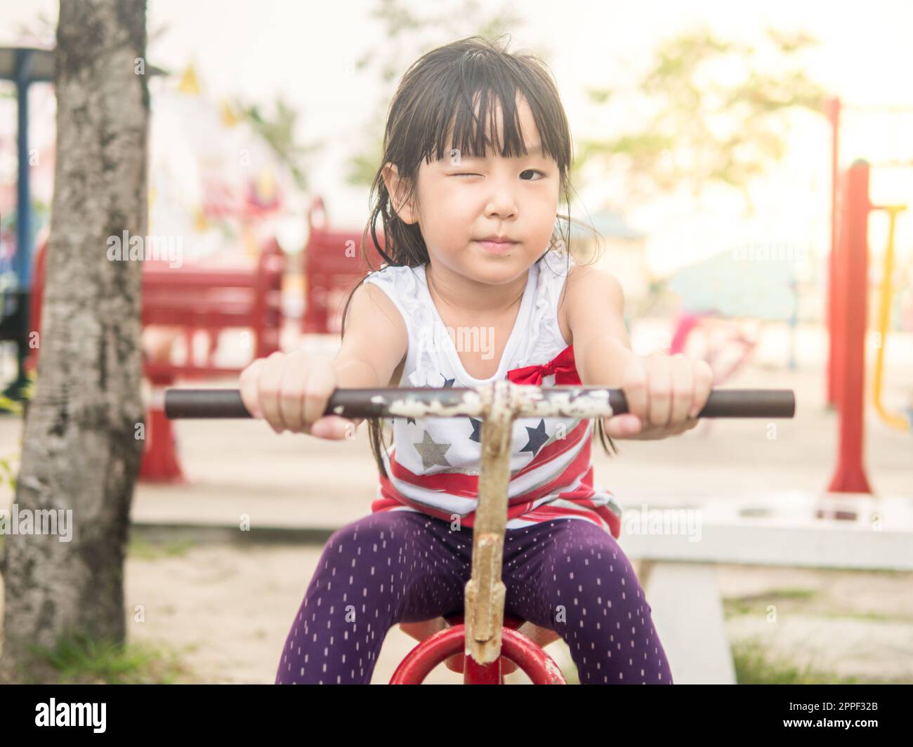 Happy asian baby child playing on playground, wink action, sunset light ...
