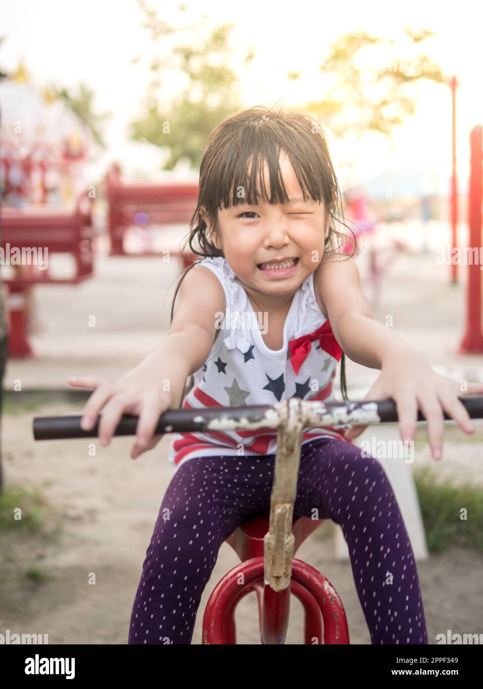 Happy asian baby child playing on playground, wink action, sunset light ...