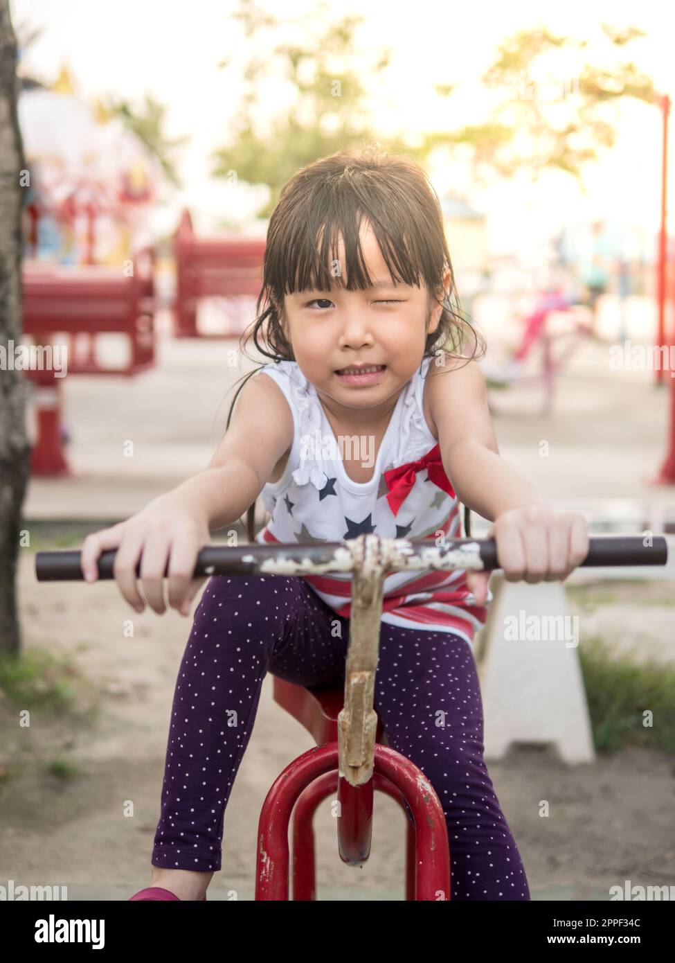 Happy asian baby child playing on playground, wink action, sunset light ...