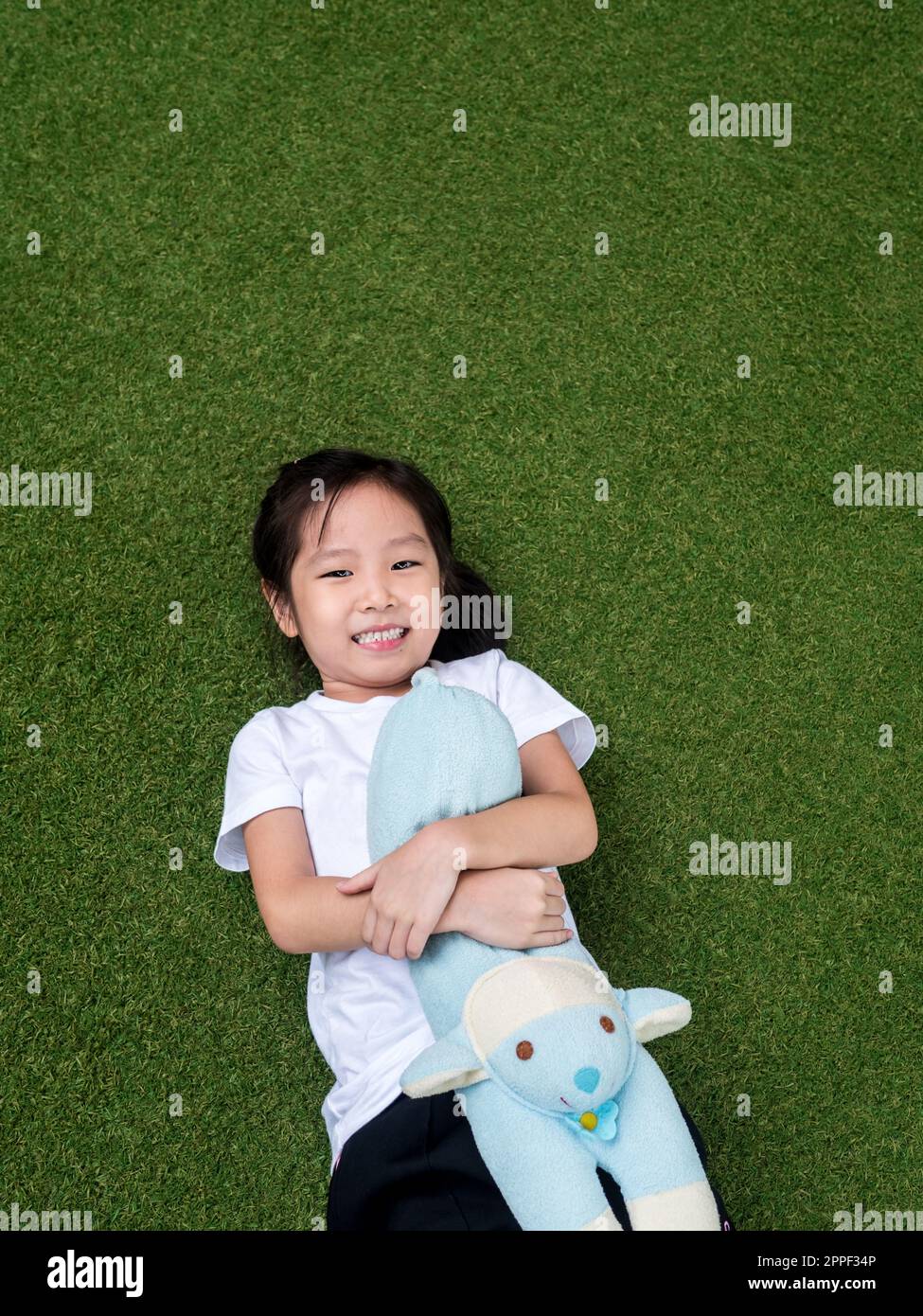 little asian kid girl lay down on the lawn with her doll Stock Photo ...