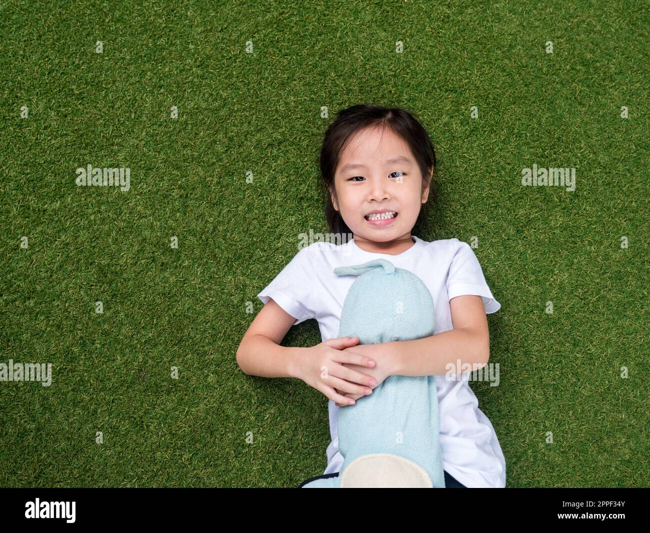 little asian kid girl lay down on the lawn with her doll Stock Photo ...
