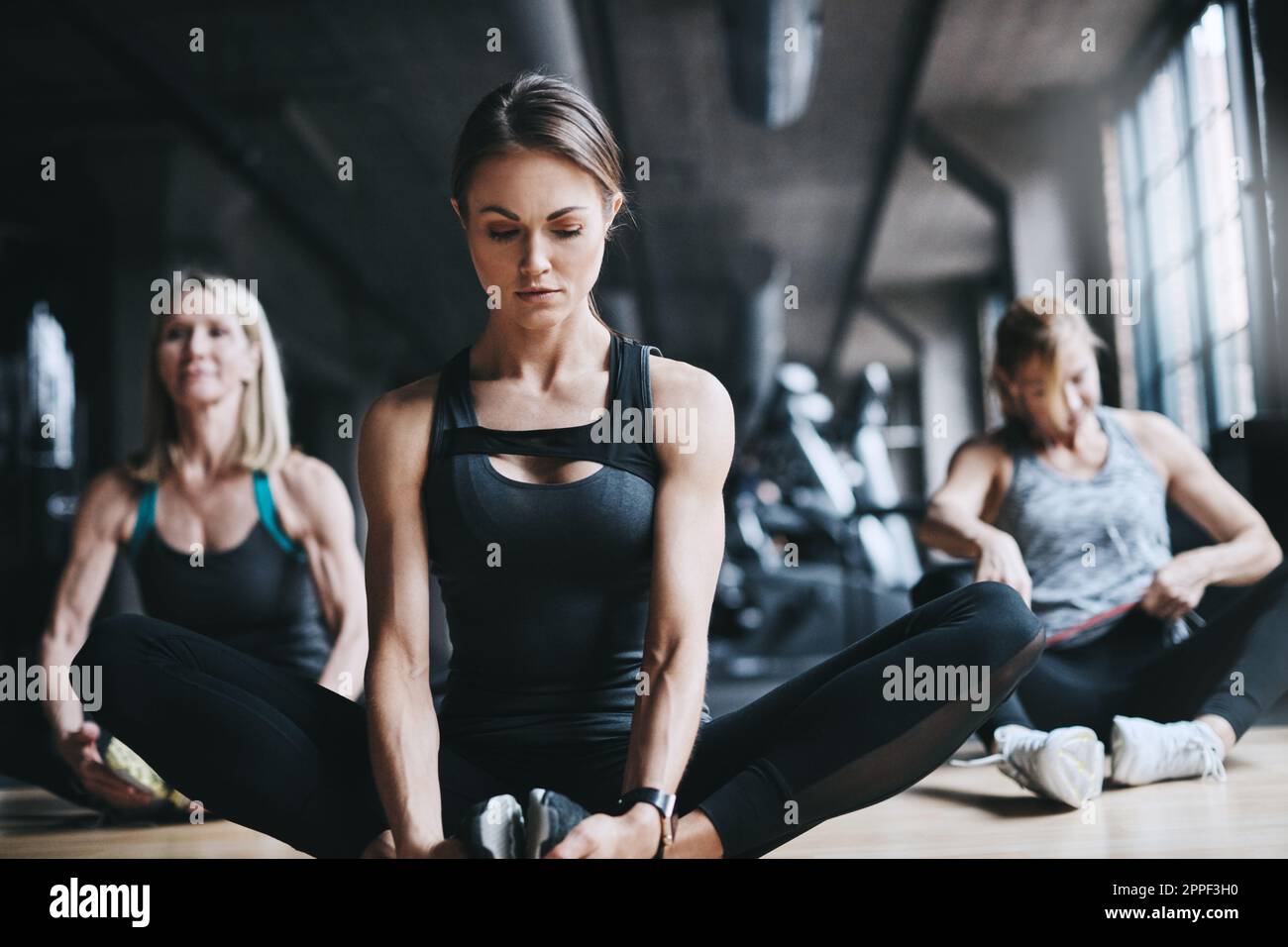 Getting into the zone. three attractive and athletic women stretching before their workout in ...