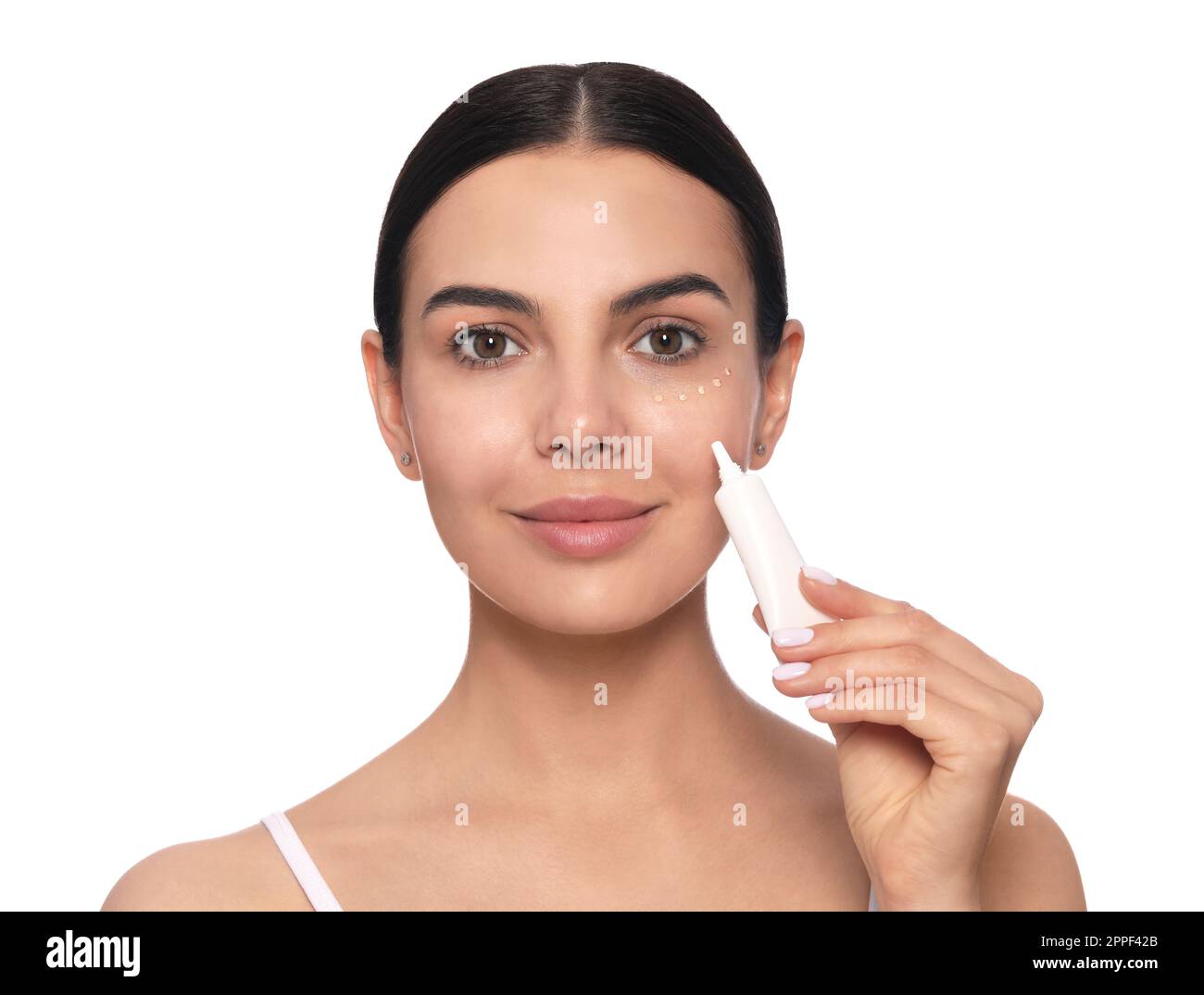 Beautiful young woman applying gel on skin under eye against white ...